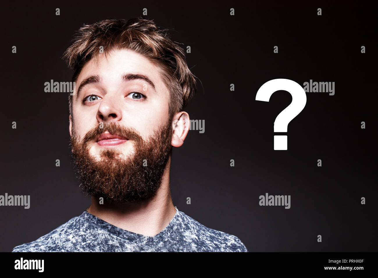 curious young guy with a beard and pretty appearance, on a dark ...