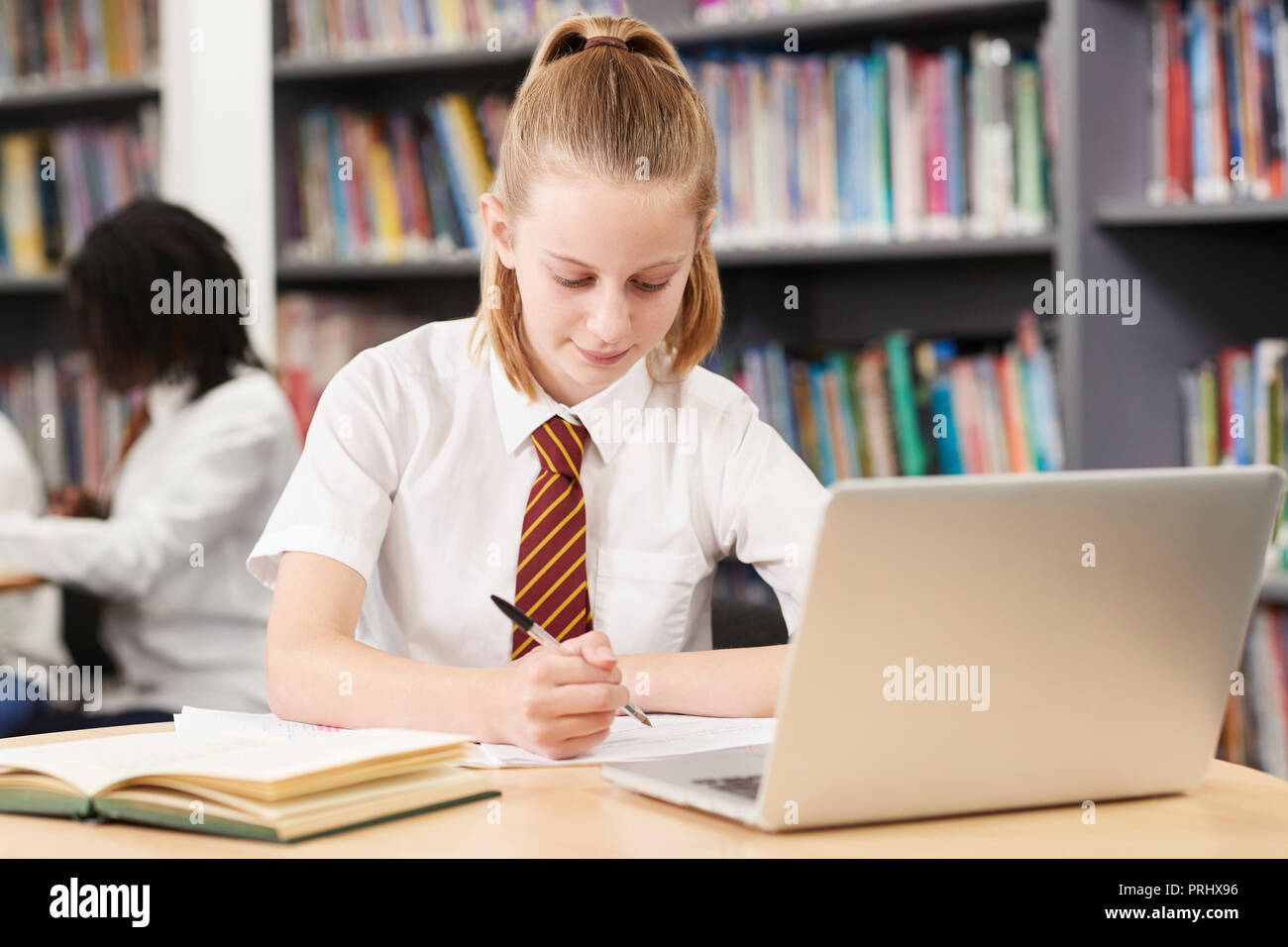Female High School Student Wearing Uniform Working At Laptop In Library ...