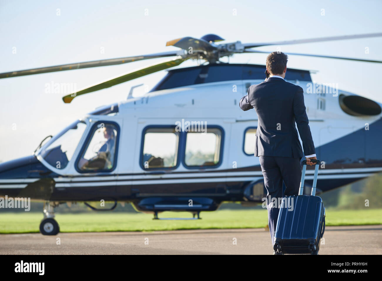 Rear View Of Businessman Walking Towards Helicopter Whilst Talking On ...