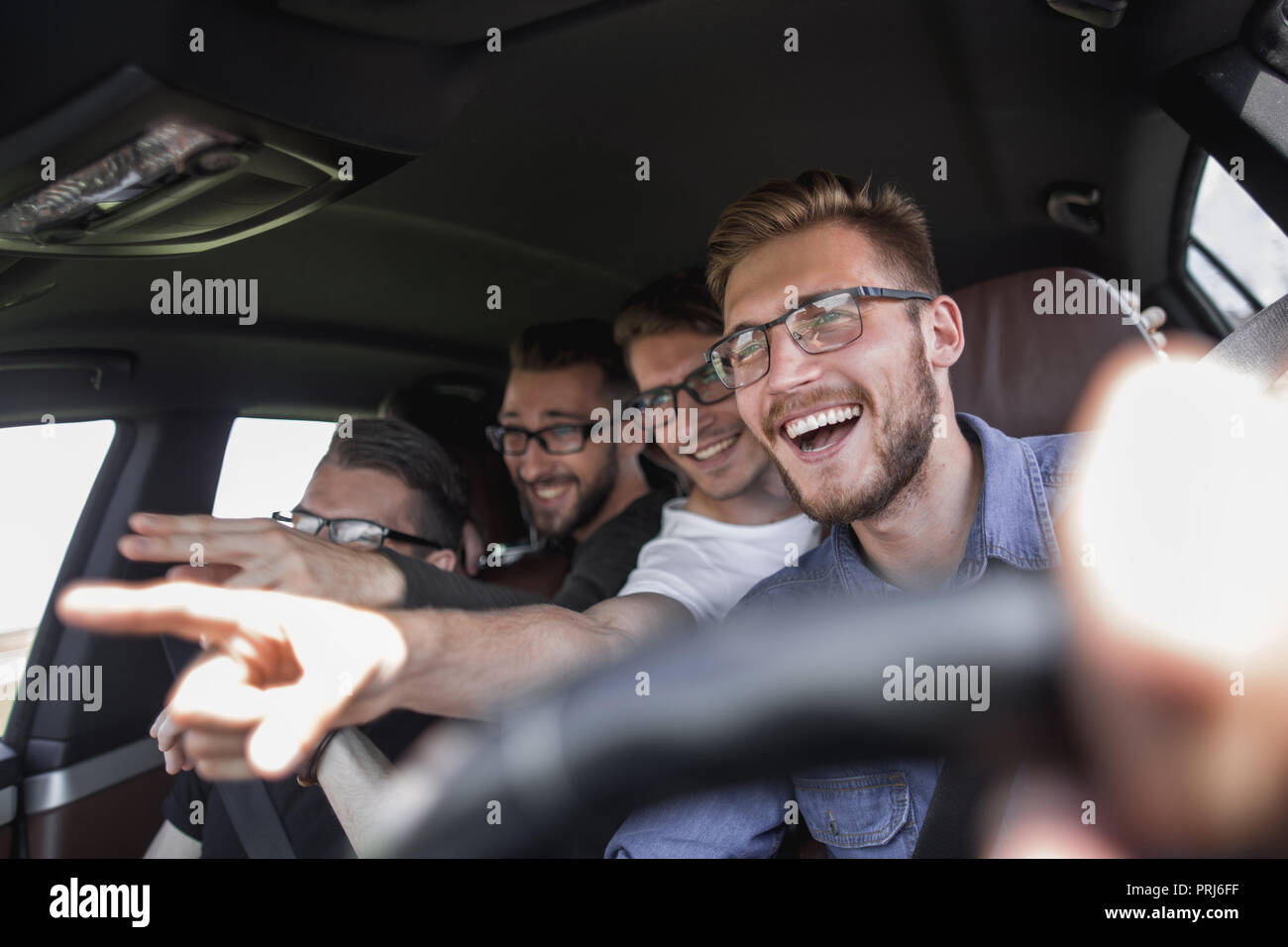 Group of happy friends on a car. Focus on the man Stock Photo - Alamy