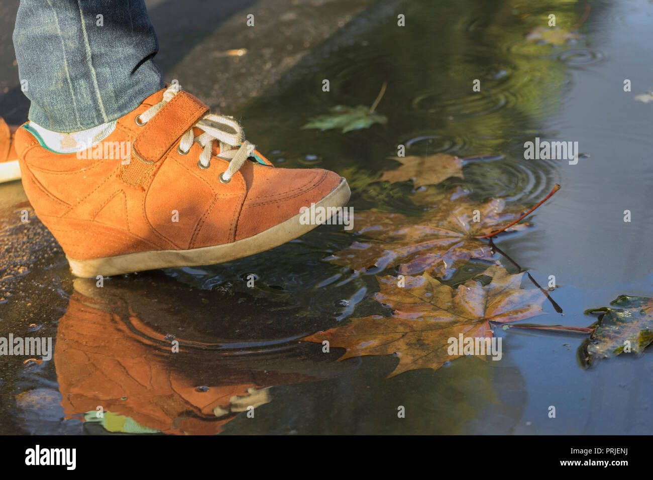 woman feet walking in a puddle in orange boots Stock Photo - Alamy