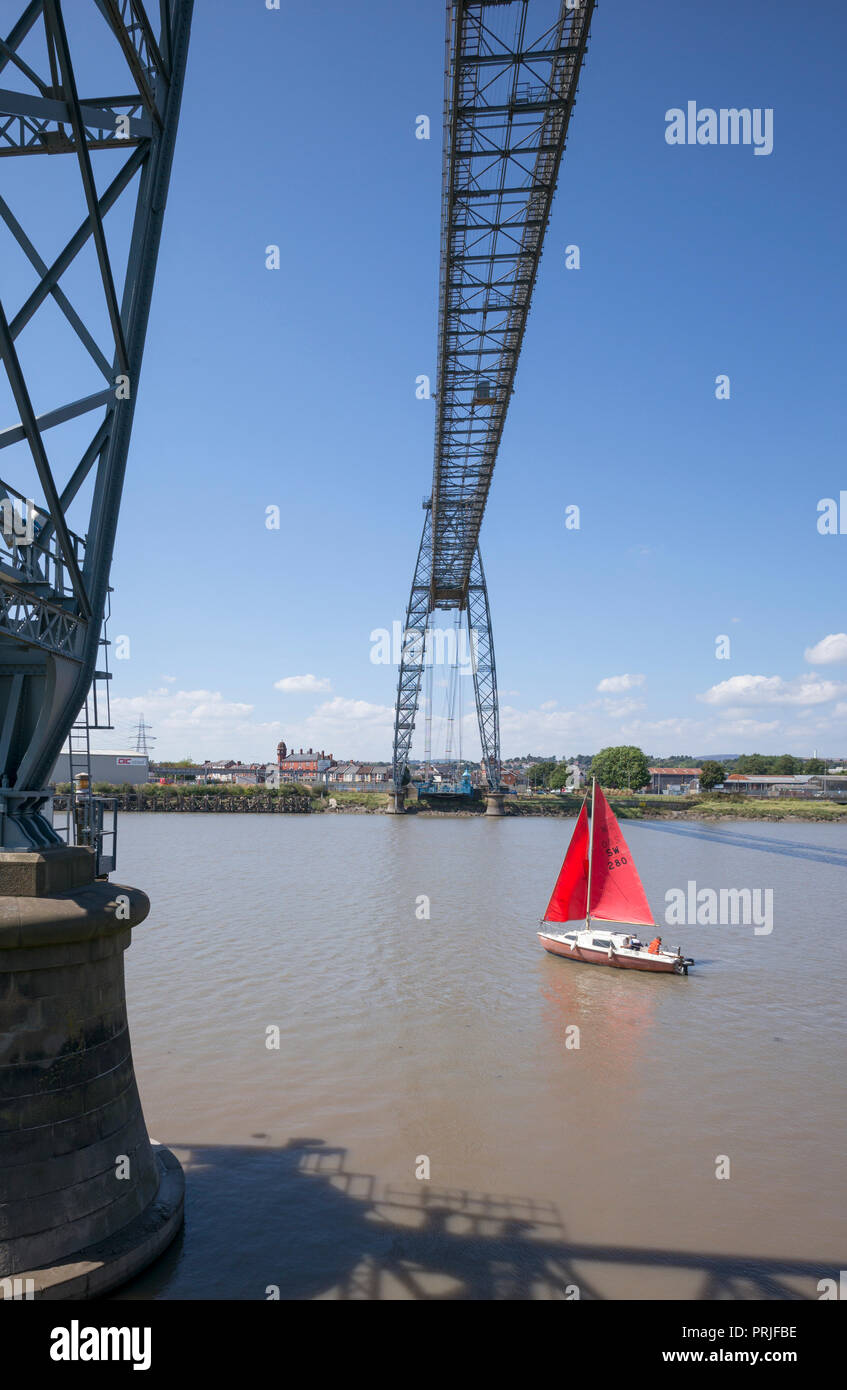 Red-sailed boat passing under Newport Transporter Bridge, Newport, UK ...