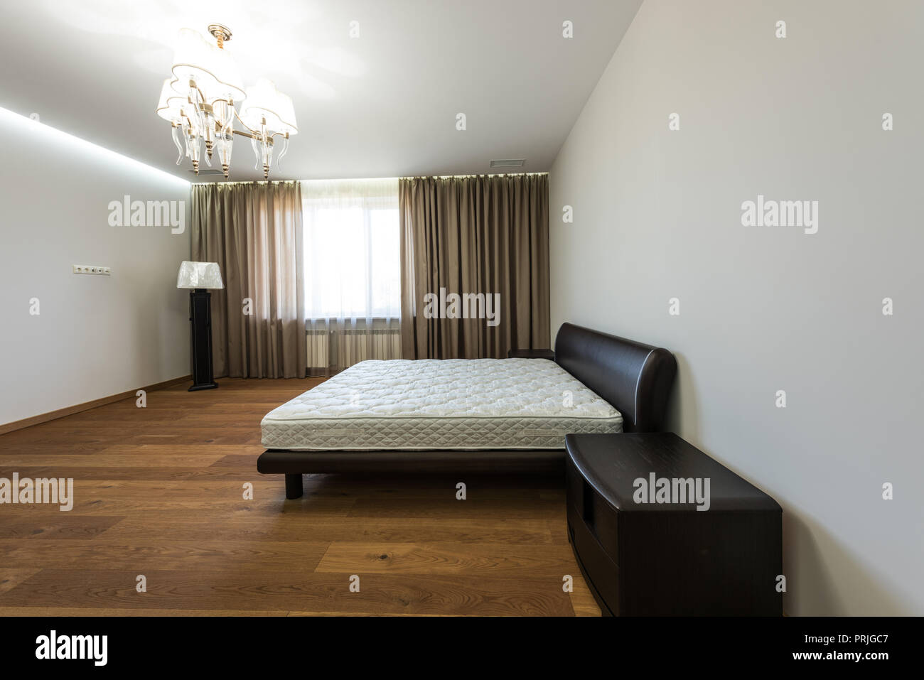 interior of empty bedroom with curtains on big window and mattress on ...