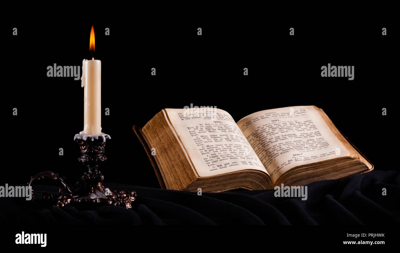 Burning candle and an open old Christian book, stilllife, Germany Stock ...