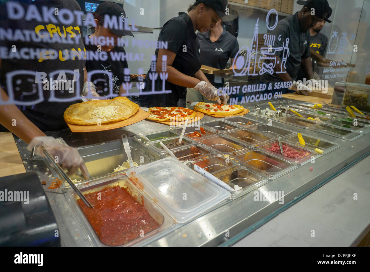 Employees construct a pizza right before the customers' eyes in ...
