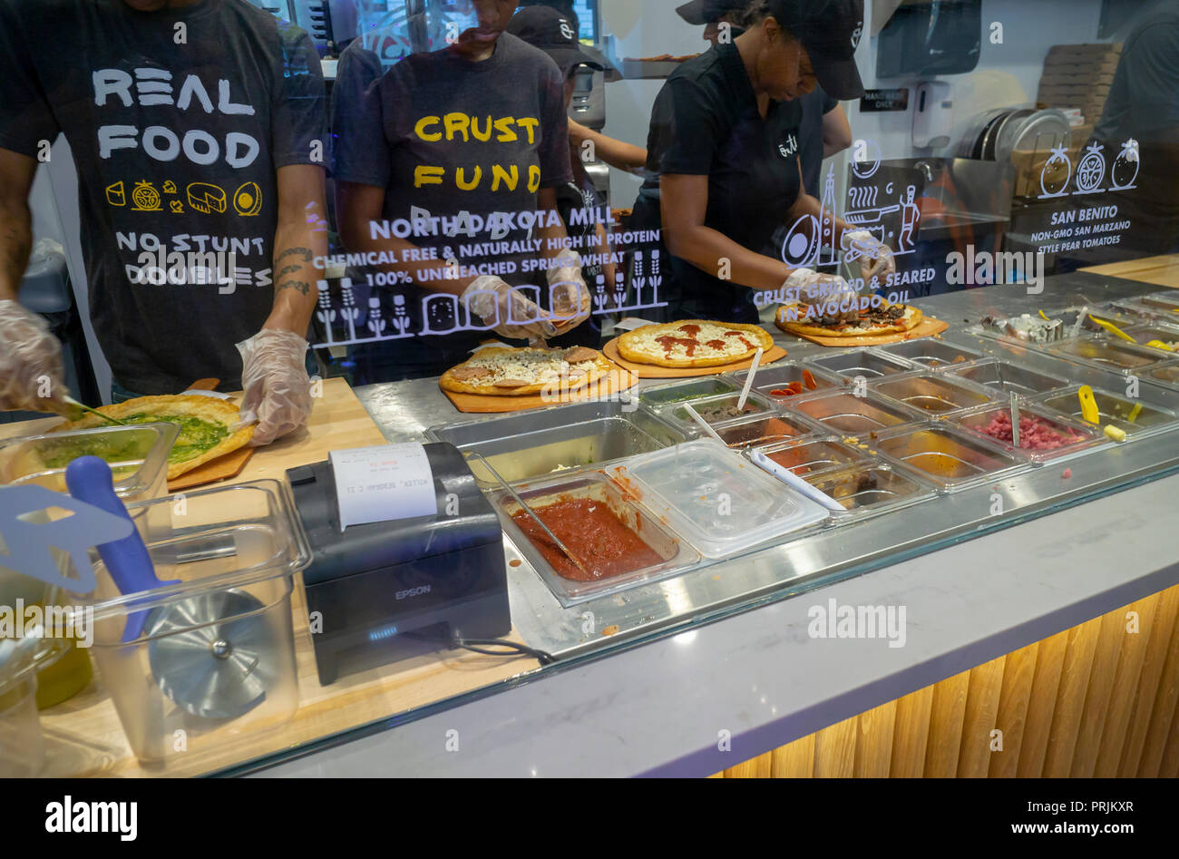 Employees construct a pizza right before the customers' eyes in ...