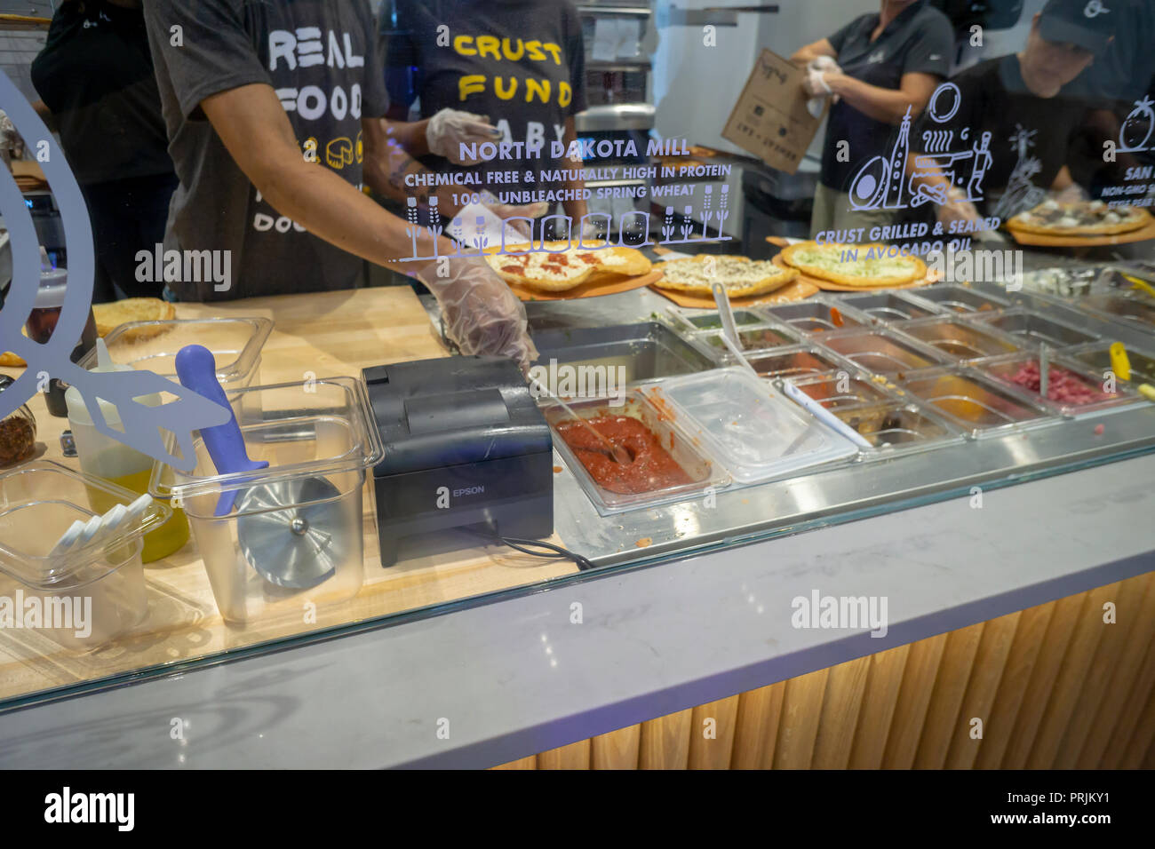Employees construct a pizza right before the customers' eyes in ...