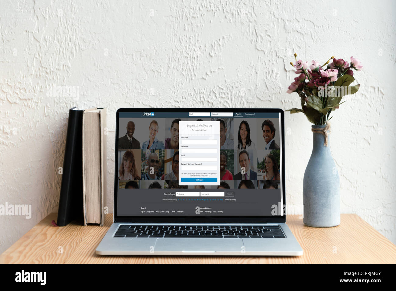 laptop with linkedin website on screen, books and flowers in vase on ...