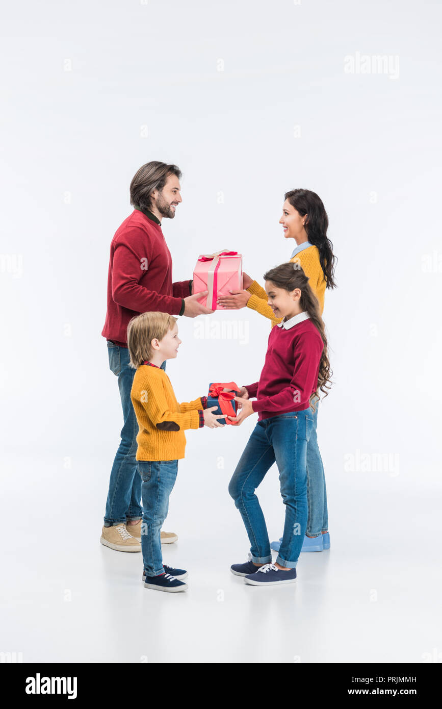 smiling parents and kids presenting wrapped gifts to each other ...