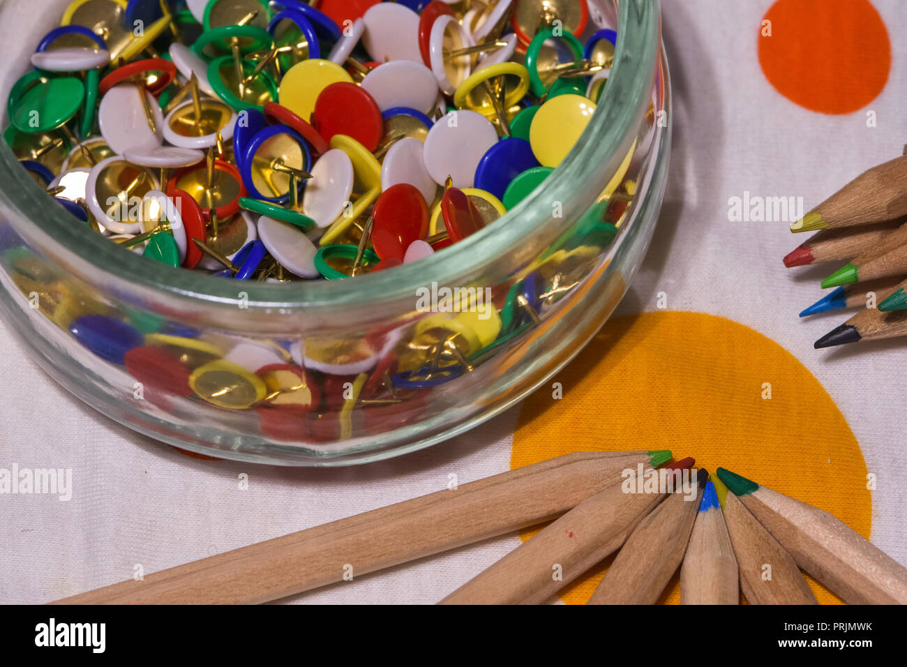 colored thumbtacks in a glass jar and colored pencils horizontal image ...