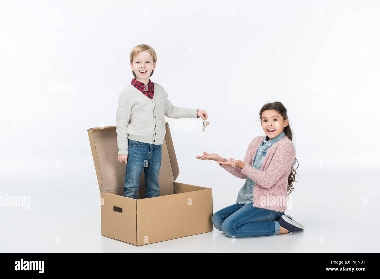 Little boy giving key from new house to surprised sister ready to move ...