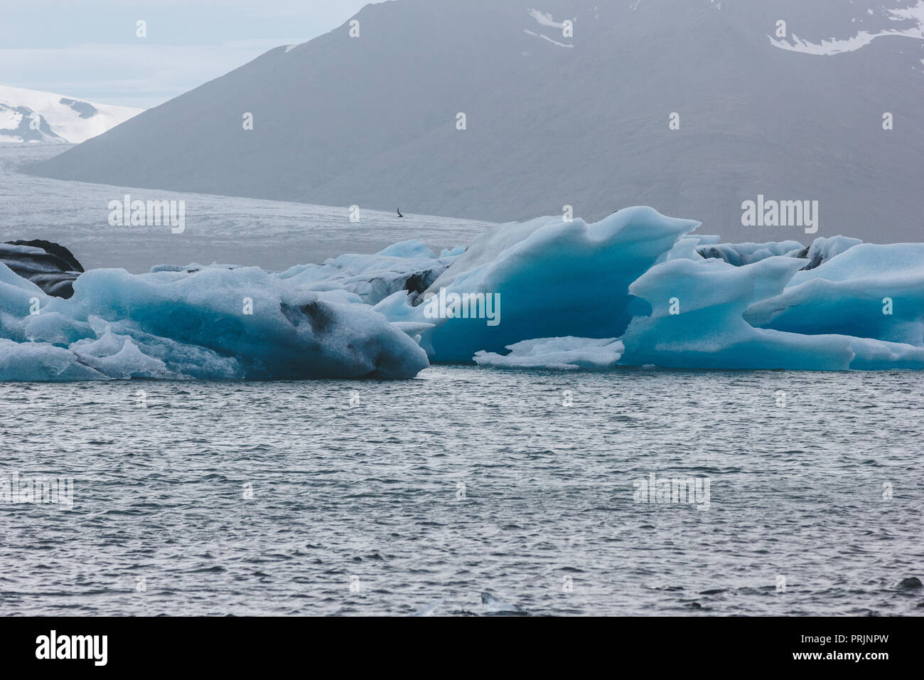 glacier ice pieces floating in lake in Iceland with mountain silhouette ...