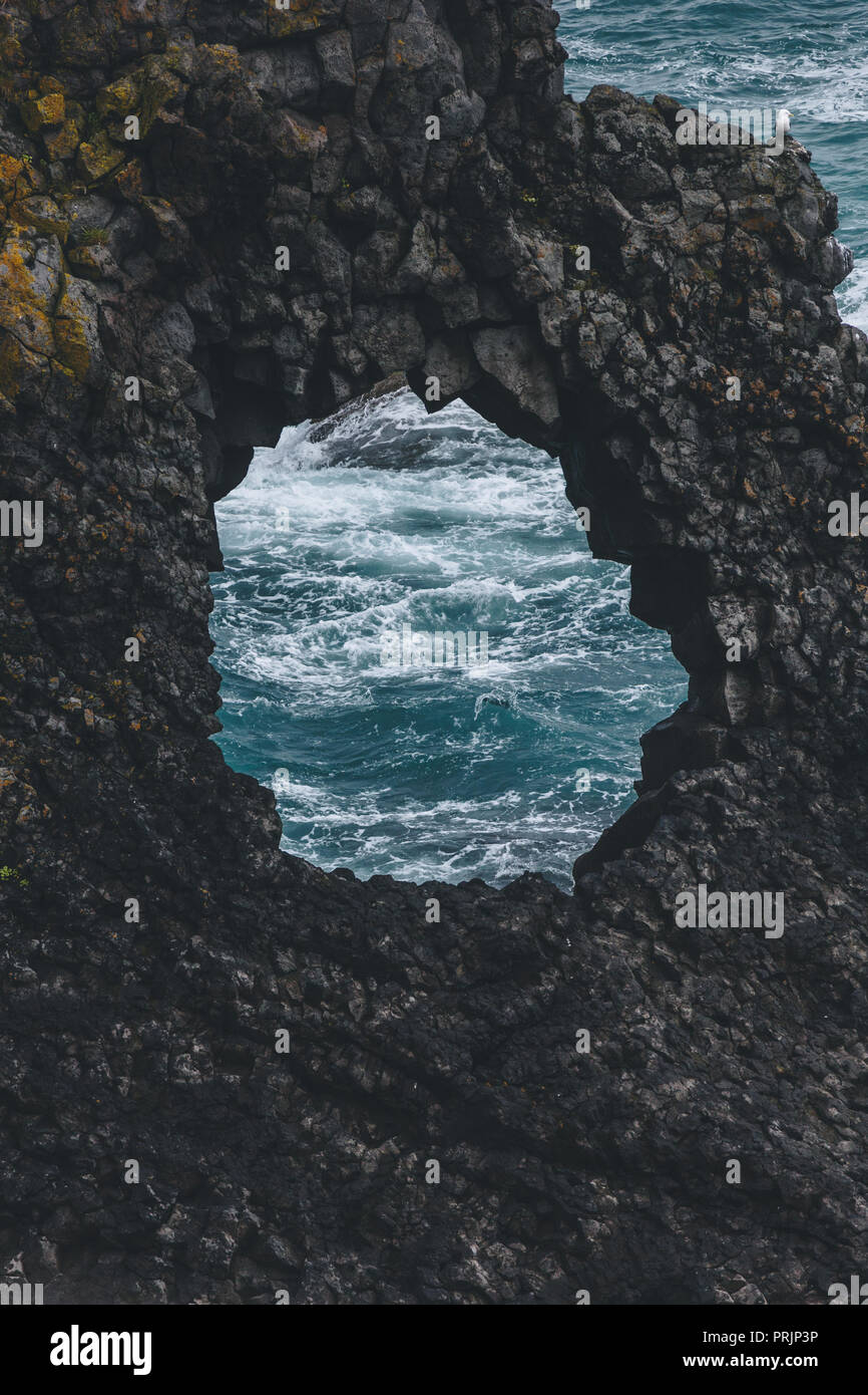 view of ocean waves through hole in cliff,Arnarstapi, Iceland Stock ...