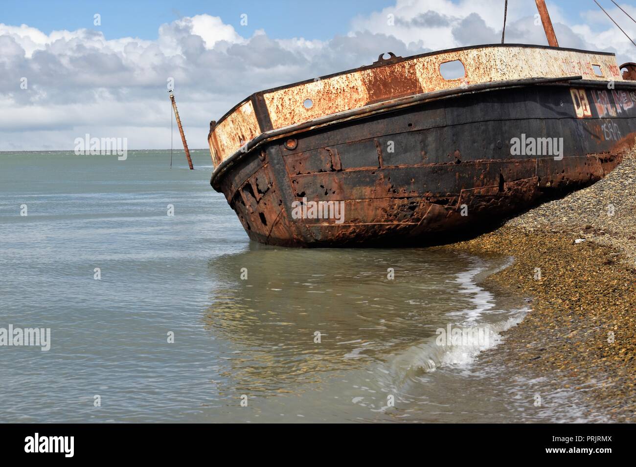 view of old rusty boat stranded on shore at high tide Stock Photo - Alamy