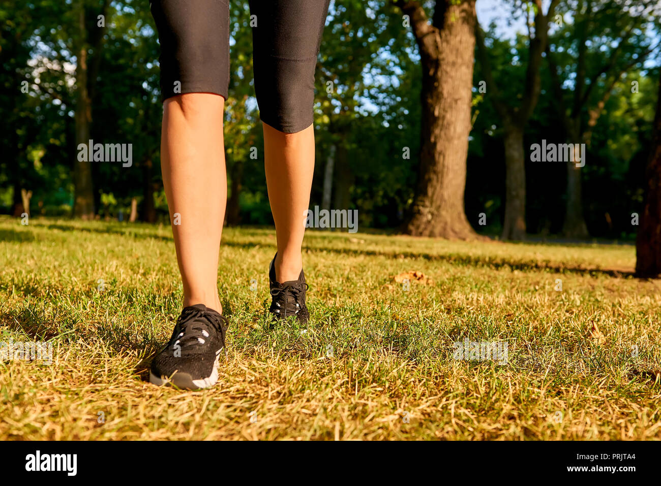 Close up of the legs of a young woman who is running off road in a park ...