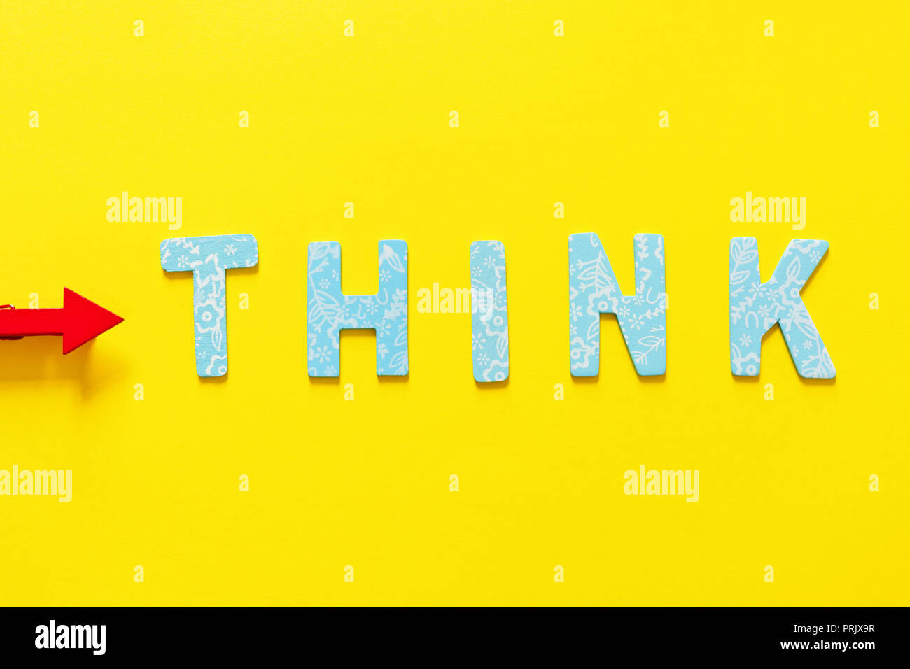 Word THINK made out of small blue wooden letter on yellow background ...
