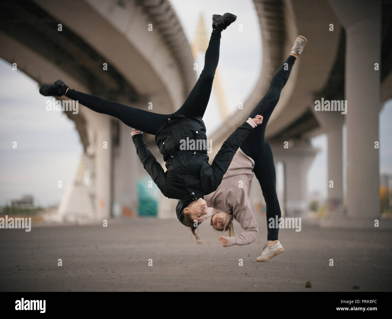 Girls perform splits in the air while jumping on the urban background ...