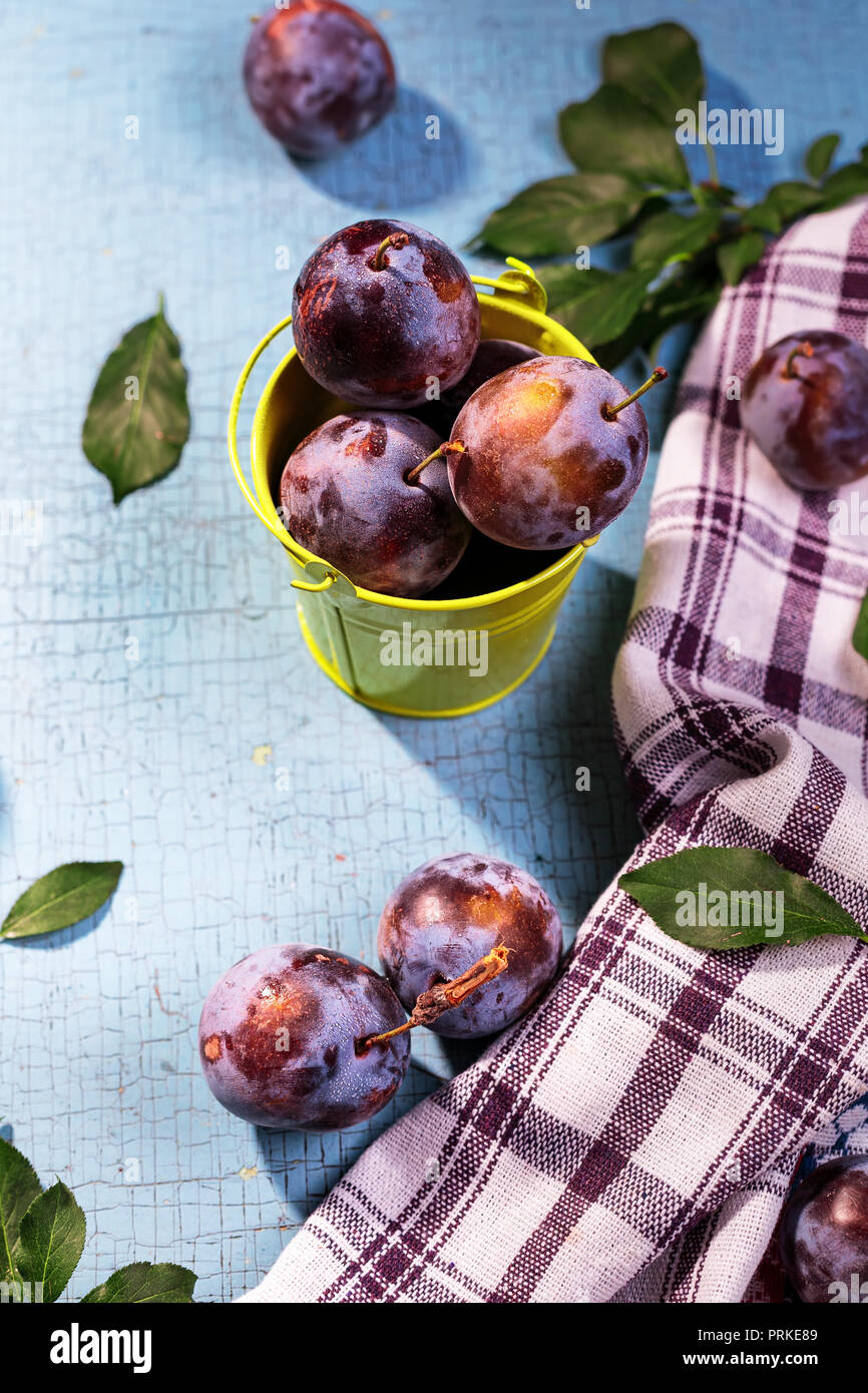 Raw plums in the bucket on wood background table Stock Photo - Alamy
