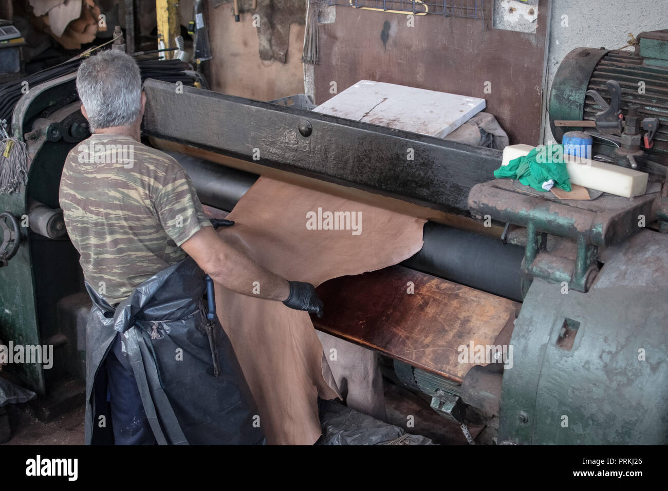 A tanner seen using a big machine to straighten the leather during the ...