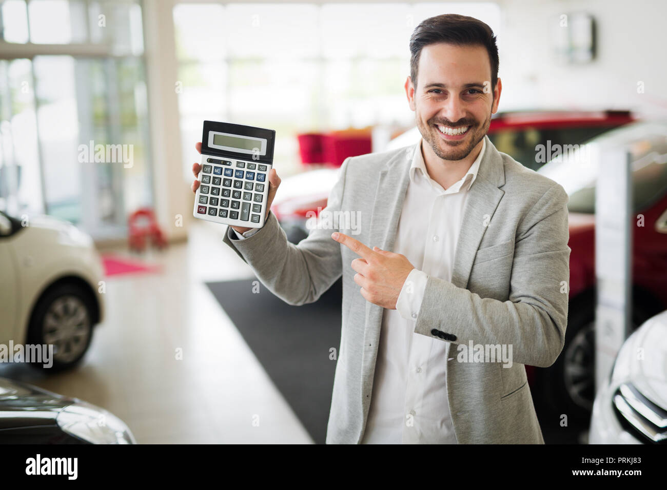Man holding a calculator in the car showroom, good price Stock Photo ...