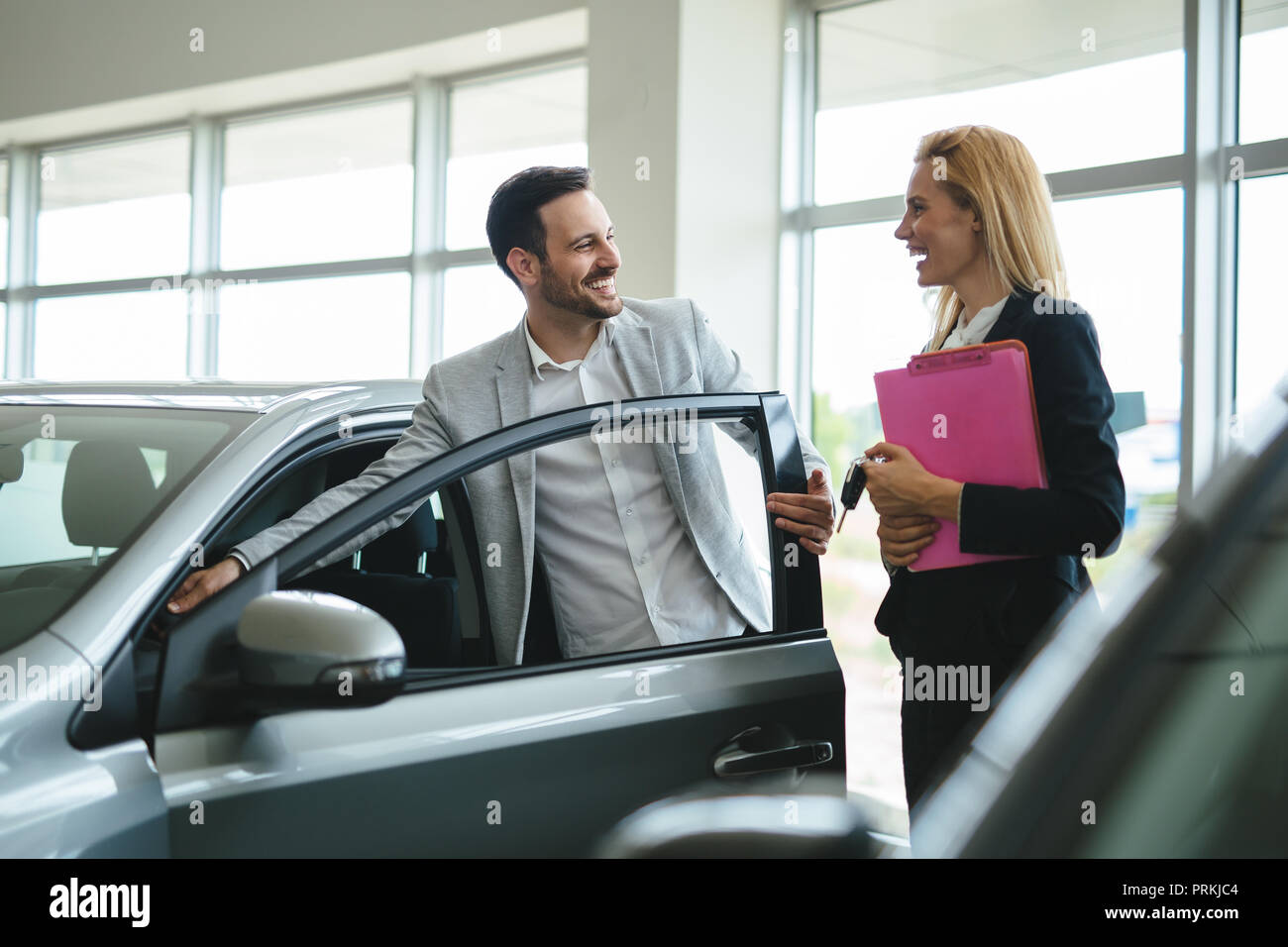 Dealer showing a new car model to the potential customer Stock Photo ...