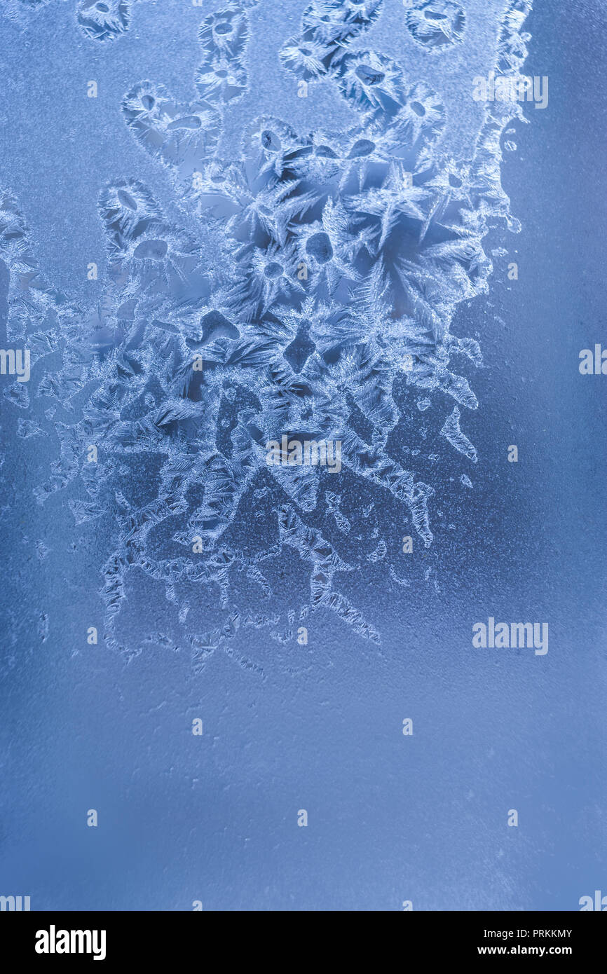 Blue frozen window with frosty pattern of snowflakes and icy crystals ...
