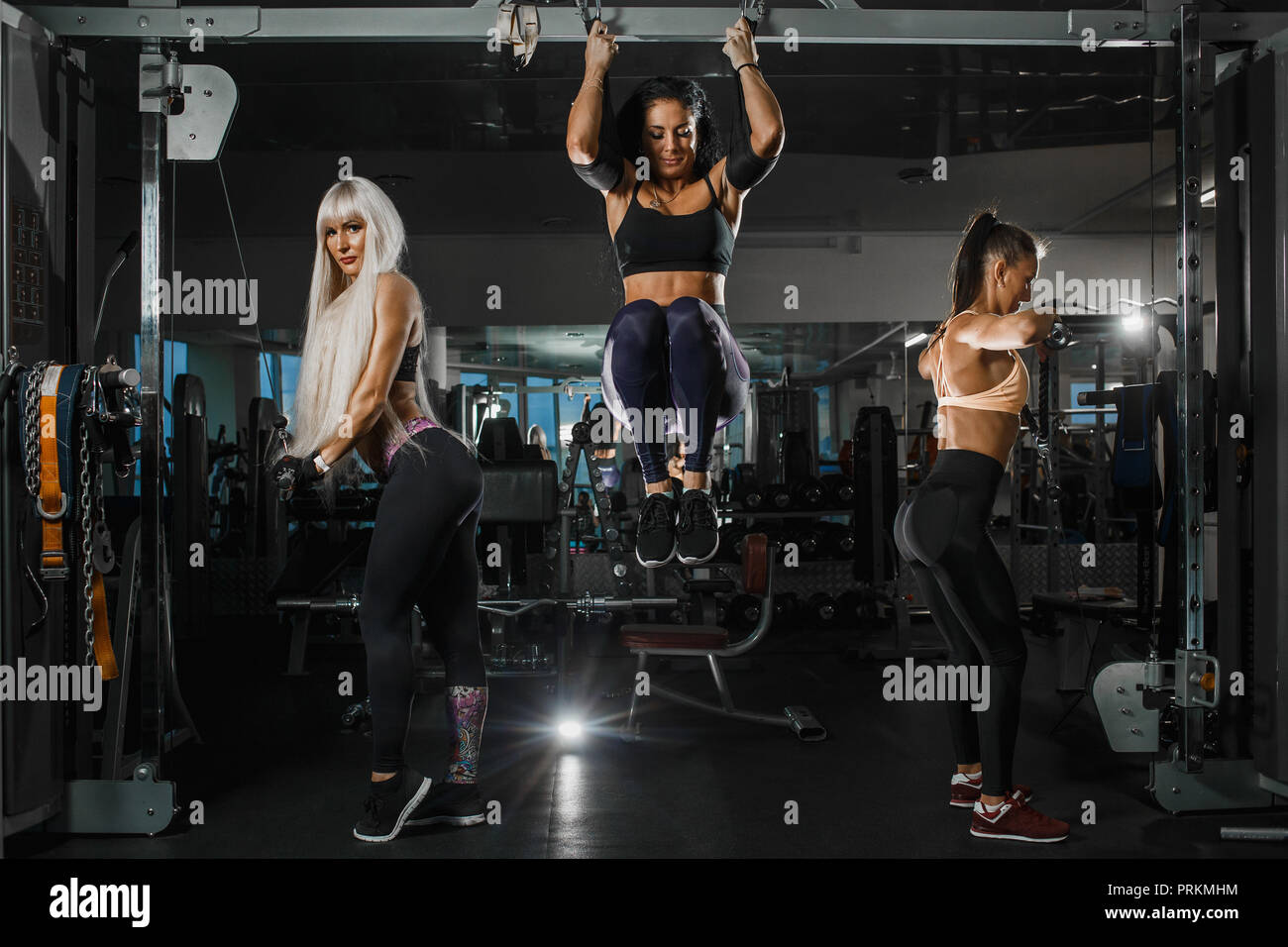 Three sports women bodybuilders intensively training on the horizontal ...