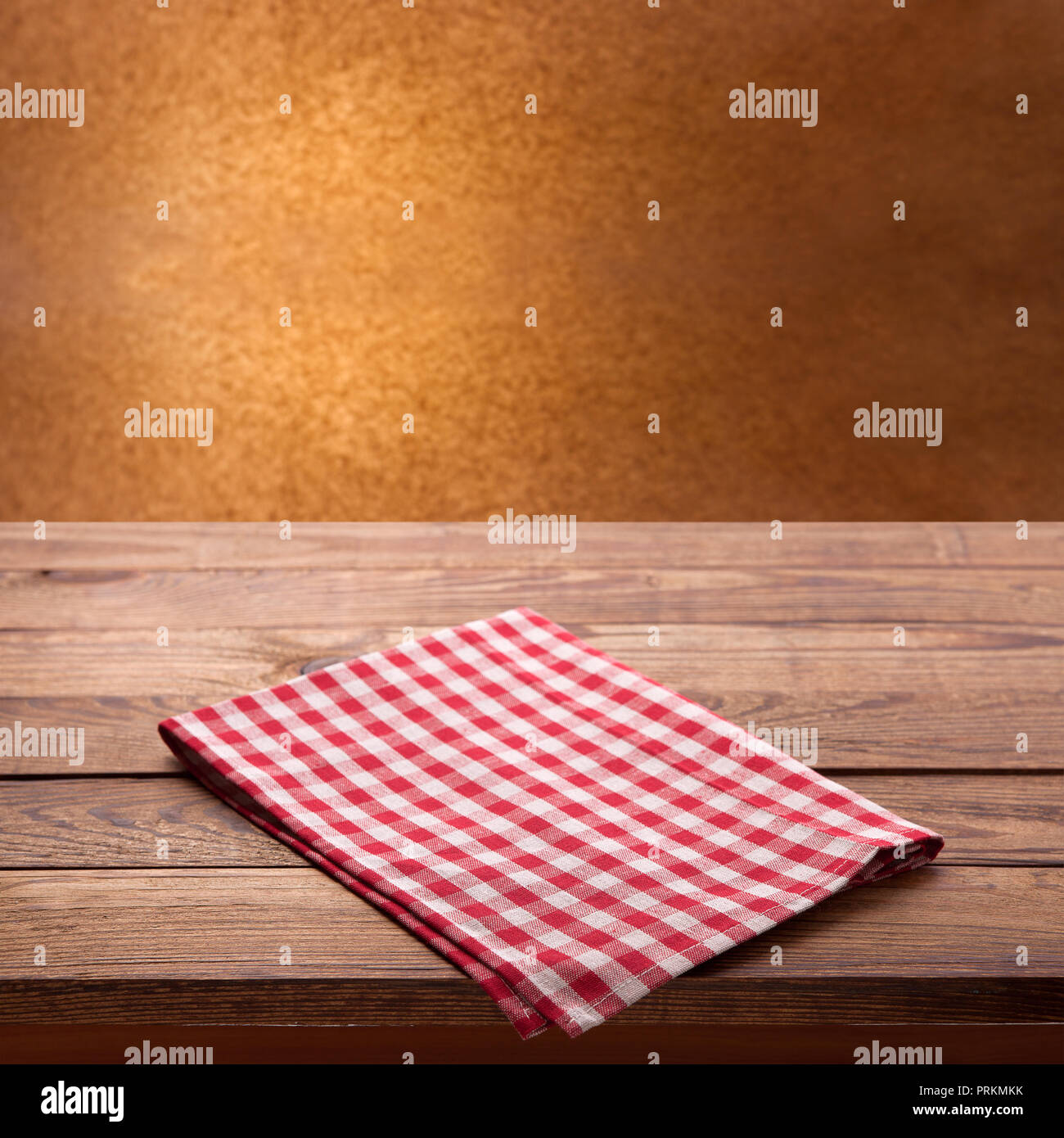 Red checkered tablecloth on empty wooden table. Napkin close up top ...