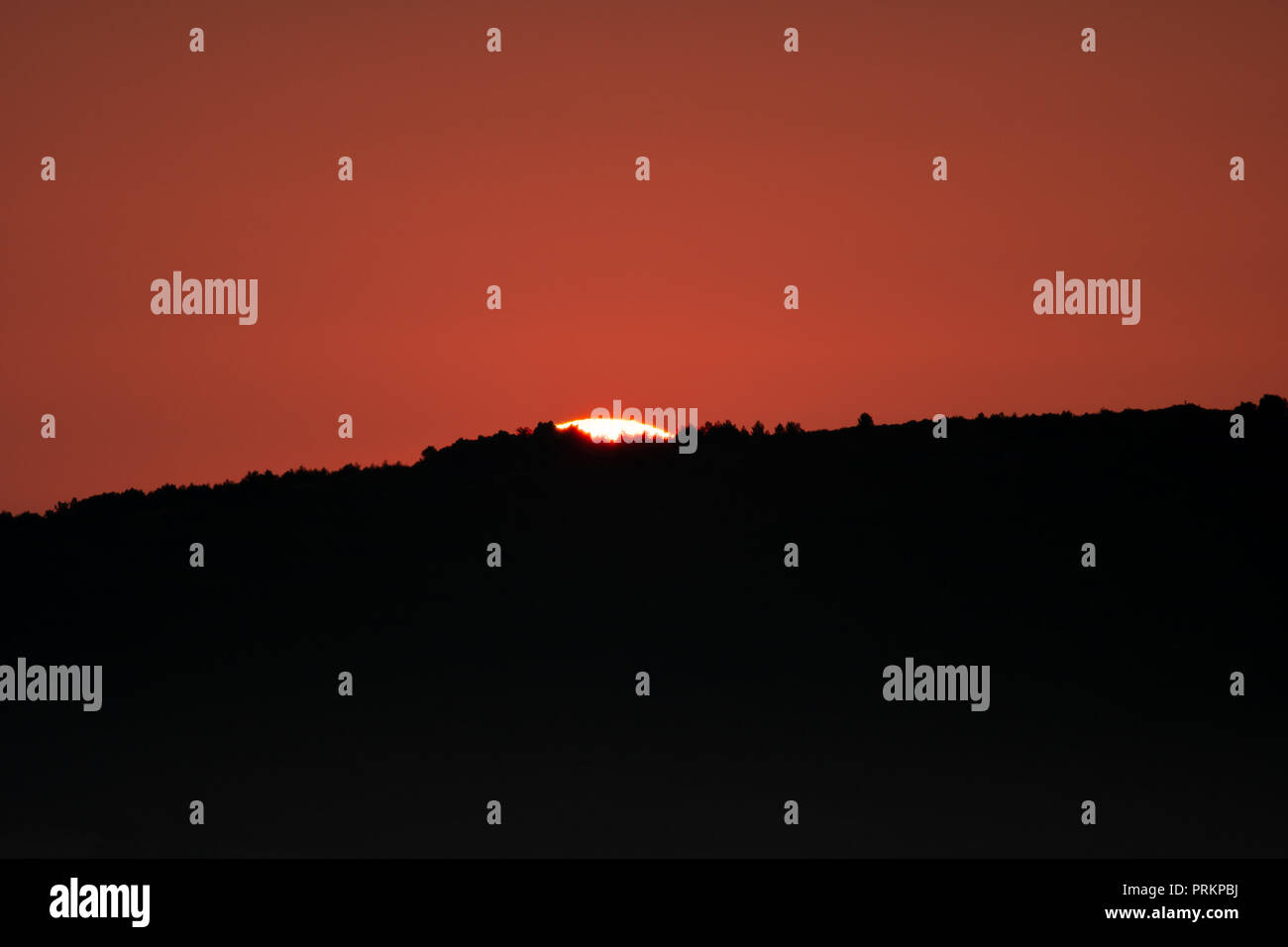 Sun rising behind the dark mountain a little bit Stock Photo - Alamy