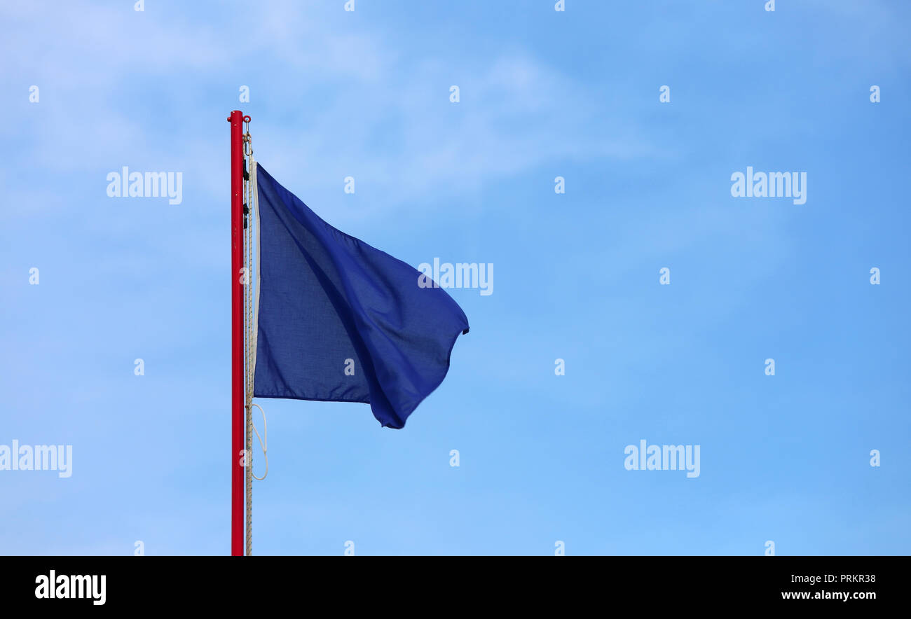 big blue flag waves on the blue sky. this is a symbol indicates an area ...