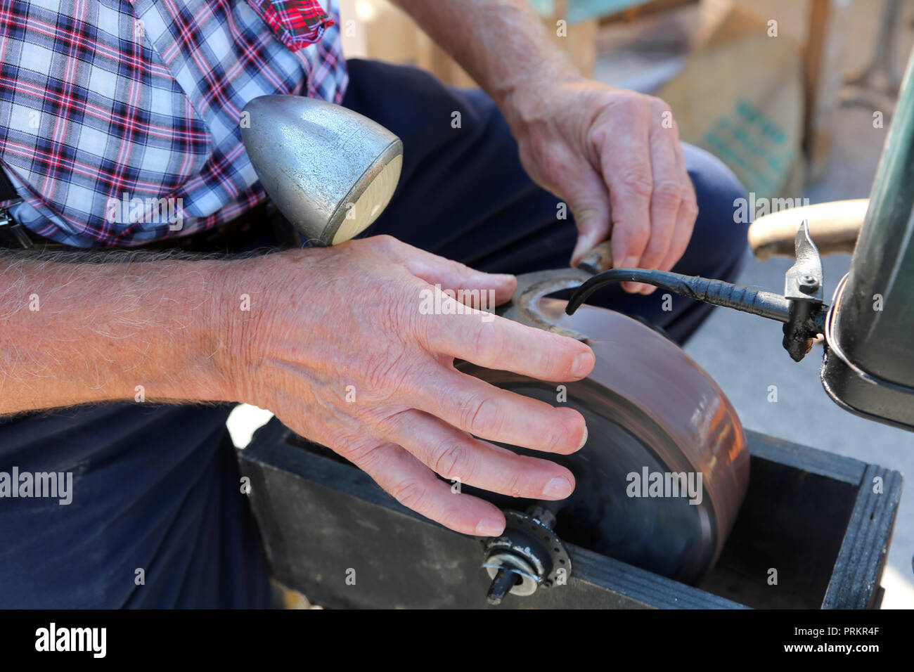 old grinder with manual grindstone grinding the blade of billhook Stock ...