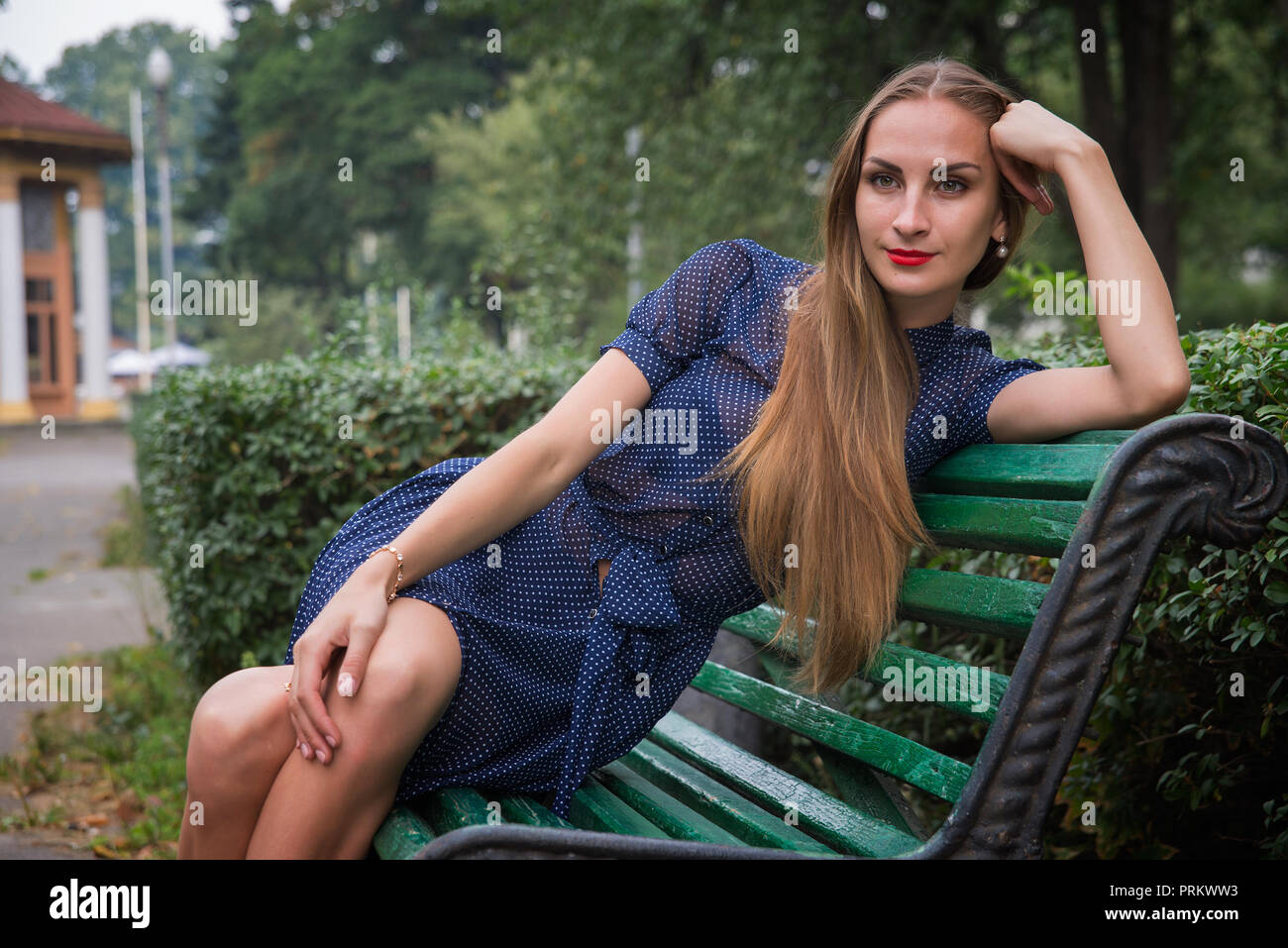 woman in a dress on a park bench Stock Photo - Alamy