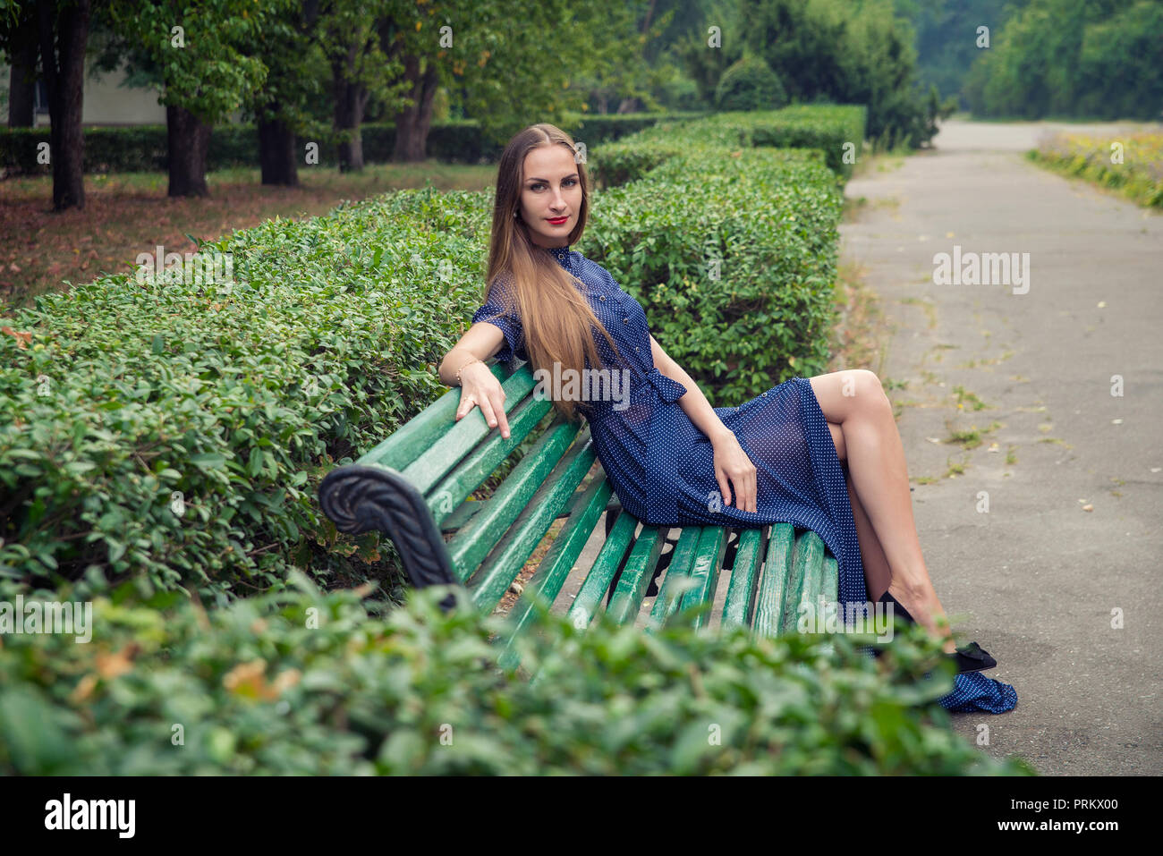 woman in a dress on a park bench Stock Photo - Alamy