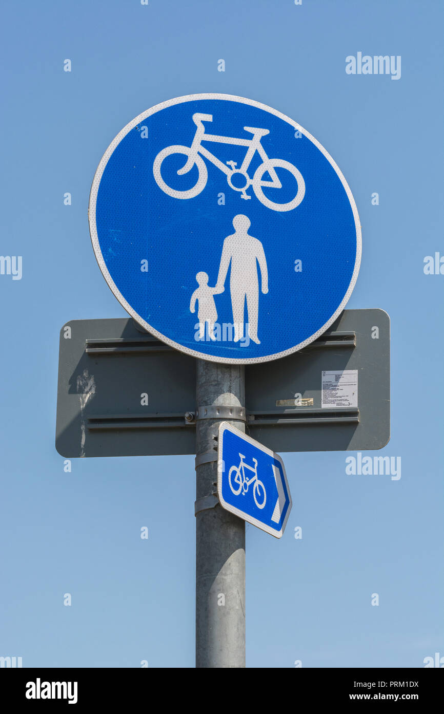 Cycle route sign with pedestrian figures set against blue summer sky in ...