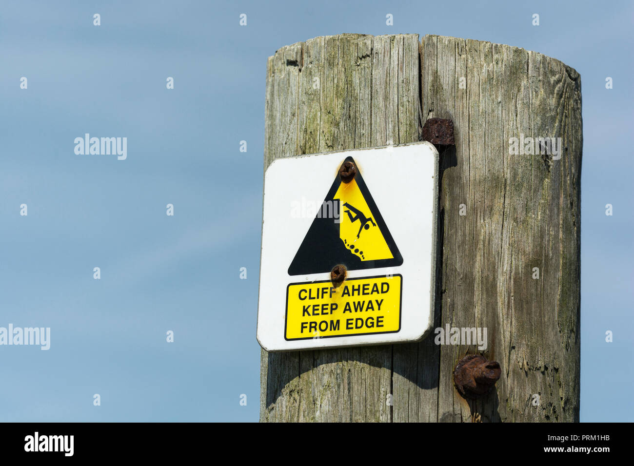 Warning yellow triangle sign highlighting dangerous cliff edge nearby ...