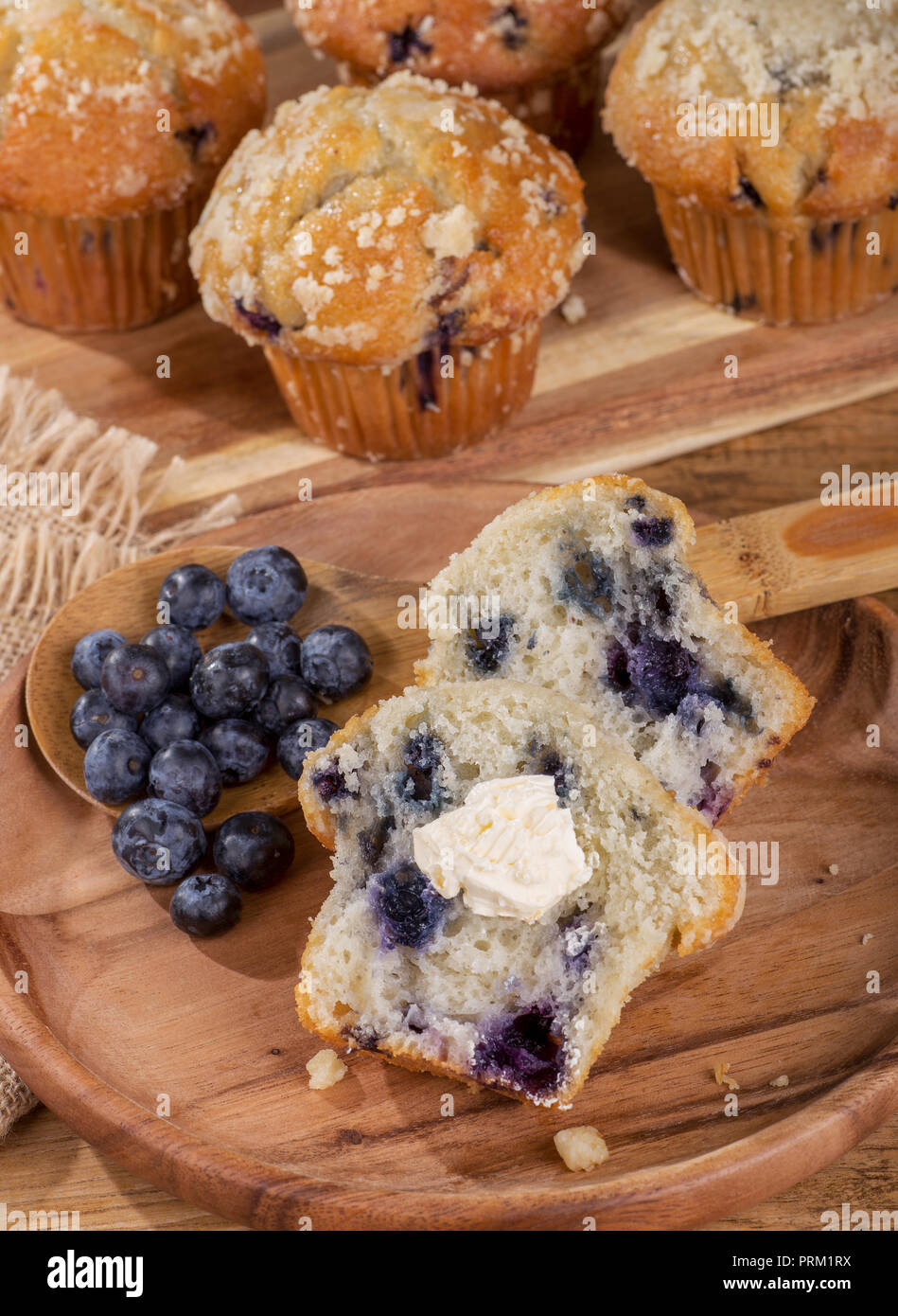 Blueberry muffin cut in half with butter and a spoonful of berries on a ...