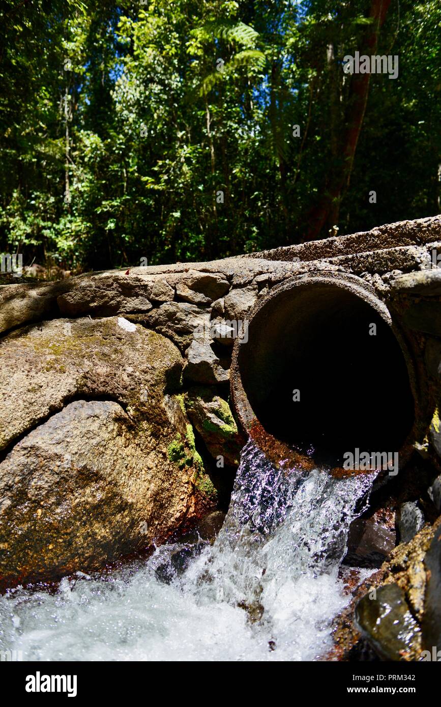 Clear water from a mountain stream flowing through a concrete pipe ...