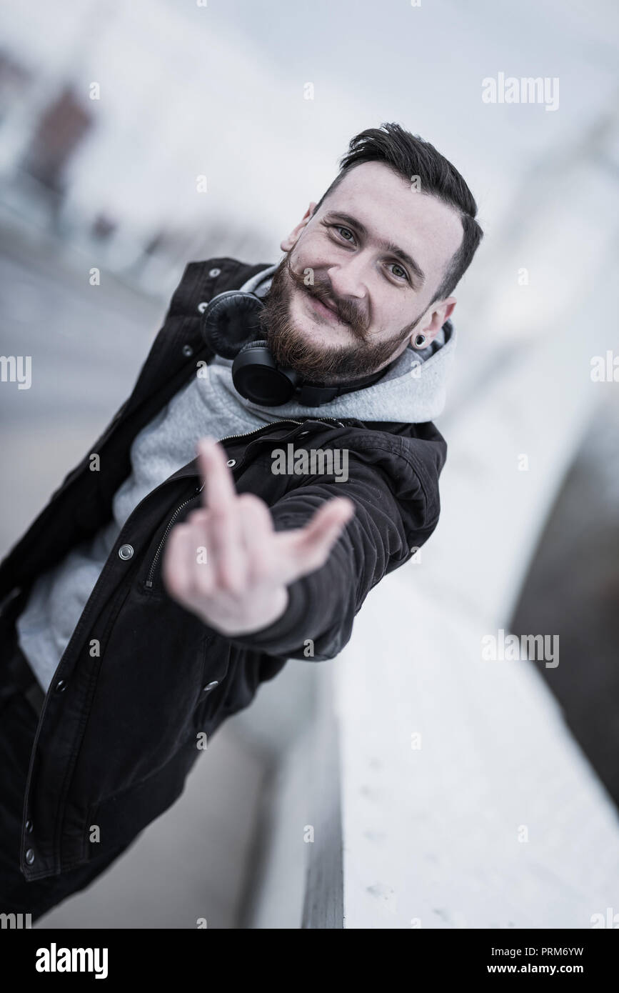 A smiling handsome young hipster man showing his middle finger to the ...