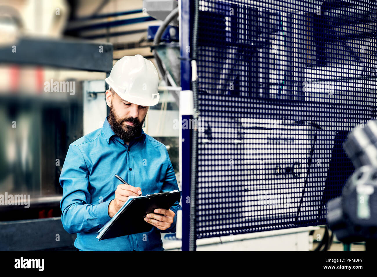 A portrait of an industrial man engineer with clipboard in a factory ...