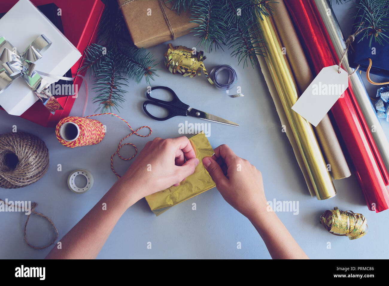 Woman's hands decorate present box on gray wooden background. New Year ...