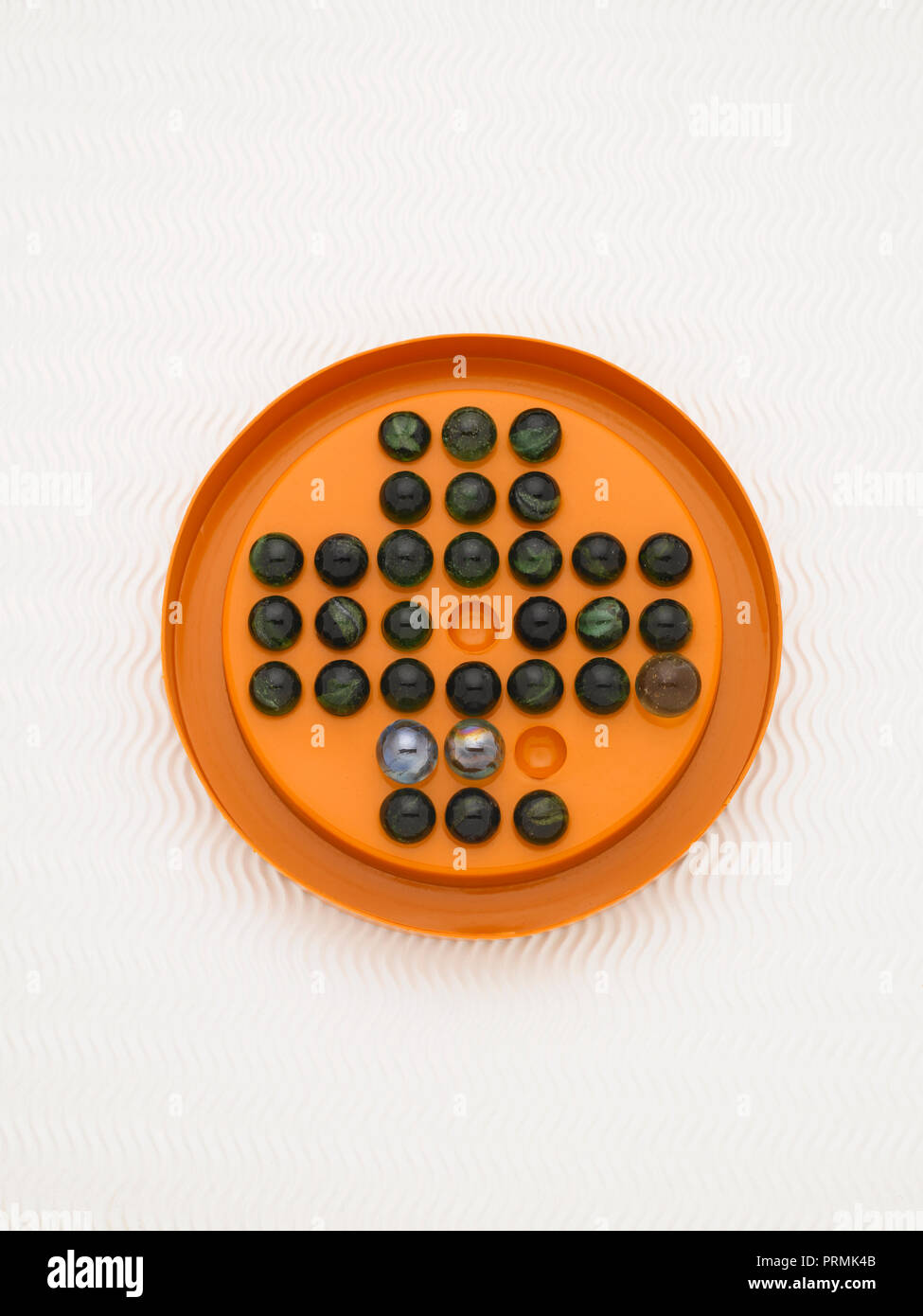 A STILL LIFE OF THE MARBLE SOLITAIRE GAME ON A WAVY WHITE BACKGROUND ...