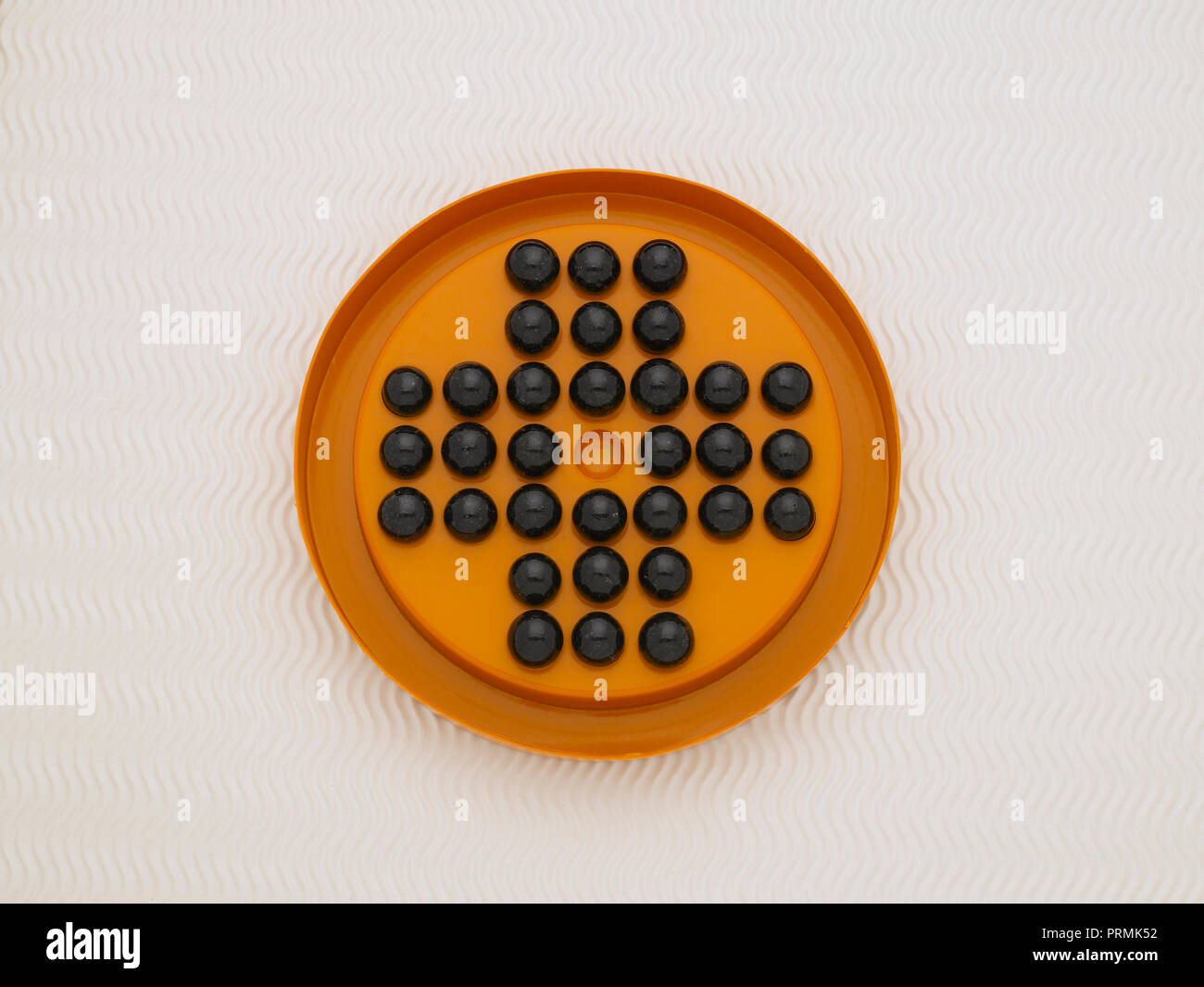 A STILL LIFE OF THE MARBLE SOLITAIRE GAME ON A WAVY WHITE BACKGROUND ...