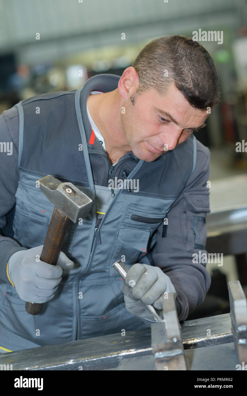one worker in factory with hammer on work bench Stock Photo - Alamy