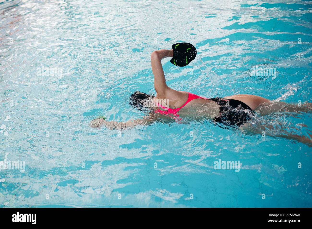 Female in pink swimwear swimming in blue water pool with special ...