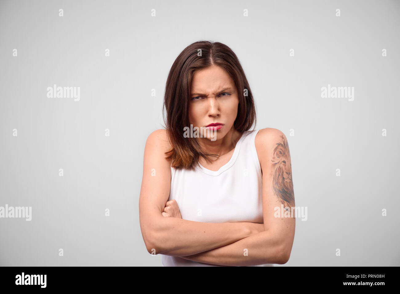Angry Annoyed Young Housewife Keeping Arms Crossed And Staring At Camera With Sceptical And