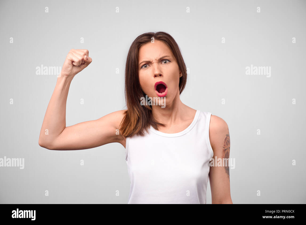 Horizontal shot of casually dressed young lady shouting fiercely and ...