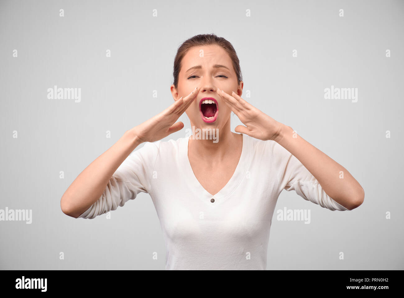 Portrait of a young lovely woman screaming out loud, isolated on a ...