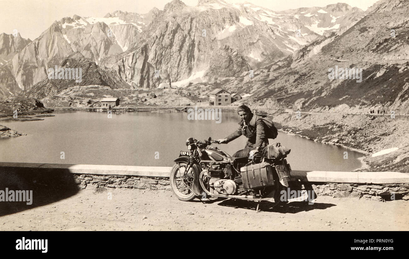 Travelling biker with rucksack on his back beside his 1936 Ariel Square ...