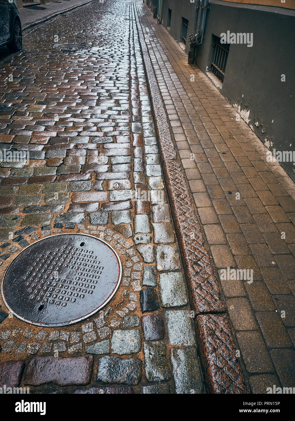 An ancient sewer hatch. The old street is covered with cobblestone ...