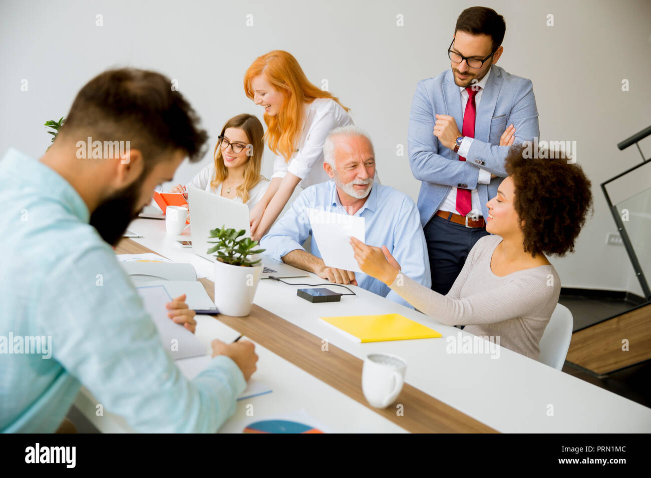 View at group of young multiracial business people around table during ...